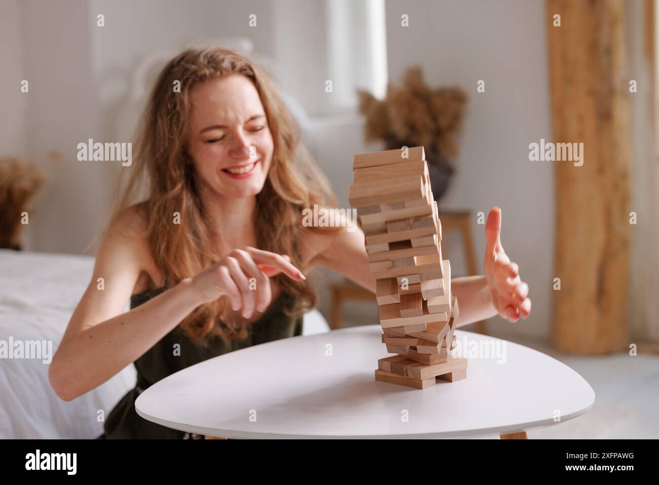 two women playing Jenga board game at home, excitement and relaxation ...
