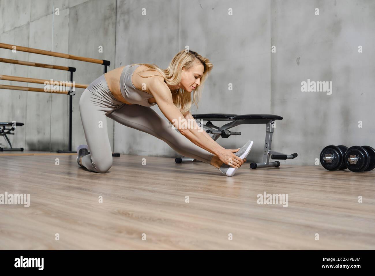 Fitness woman bends forward stretching the muscles of her back and legs ...
