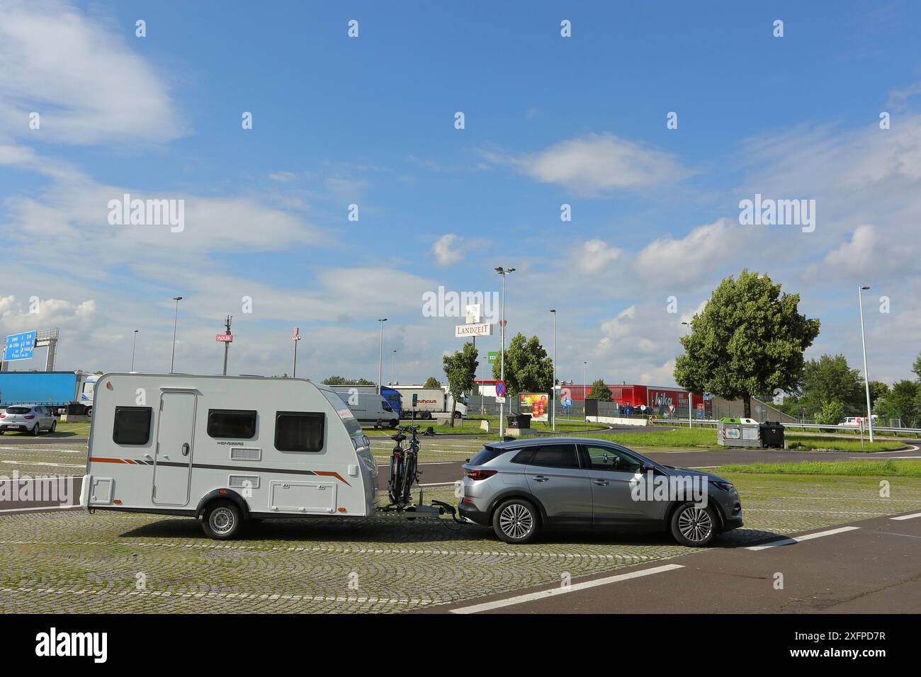 Car with caravan standing on a motorway service area, Tank und Rast ...