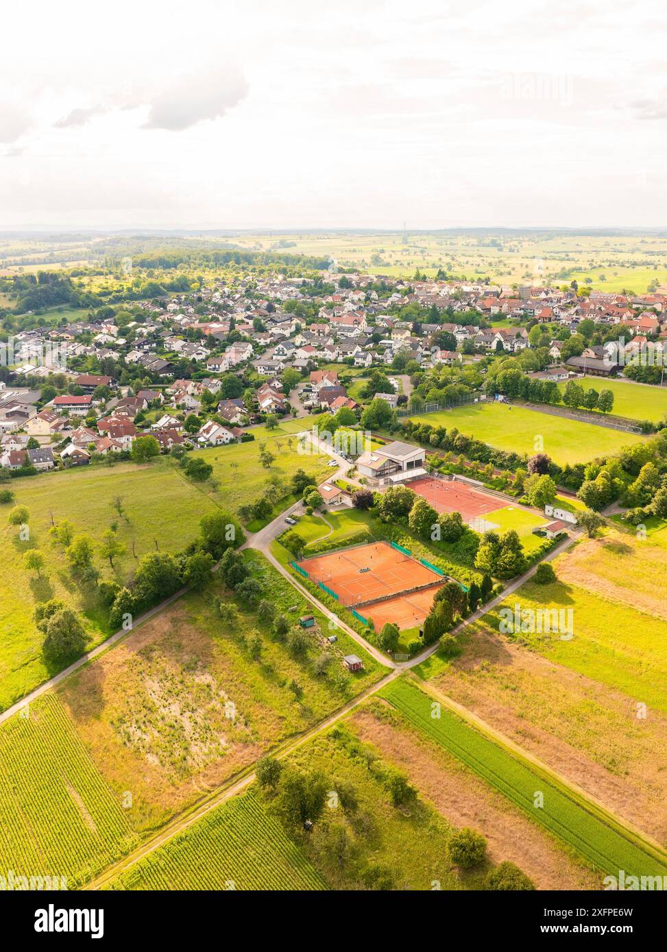 Aerial view of a town with neighbouring fields and a tennis court ...
