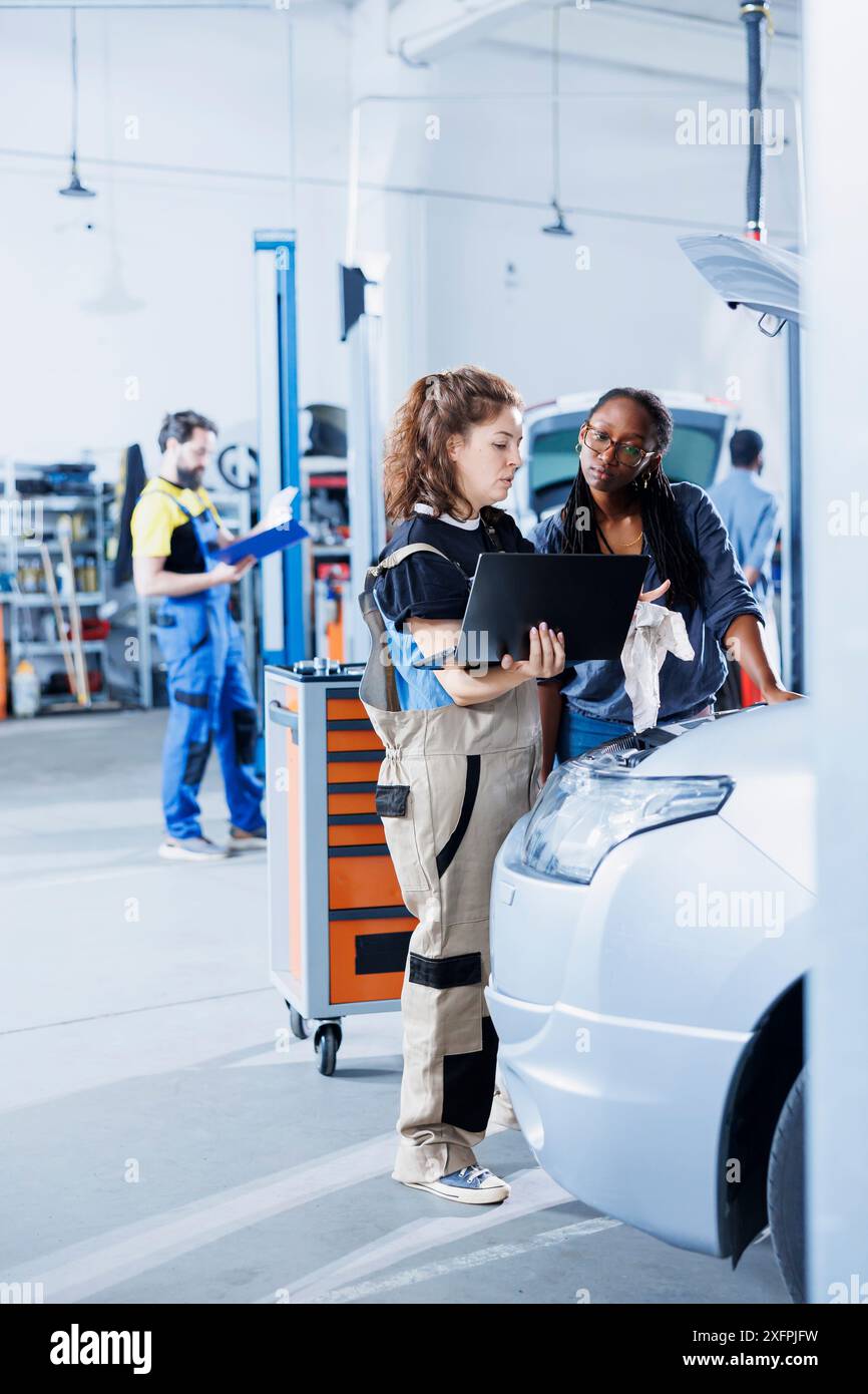 Mechanic in car service uses laptop to calculate invoice after fixing ...
