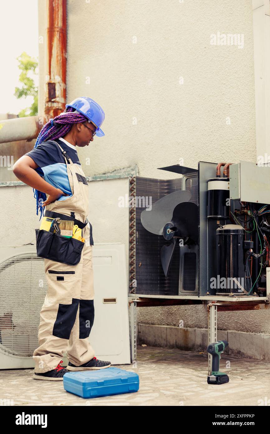 Licensed mechanic looking at opened external air conditioner, puzzled ...