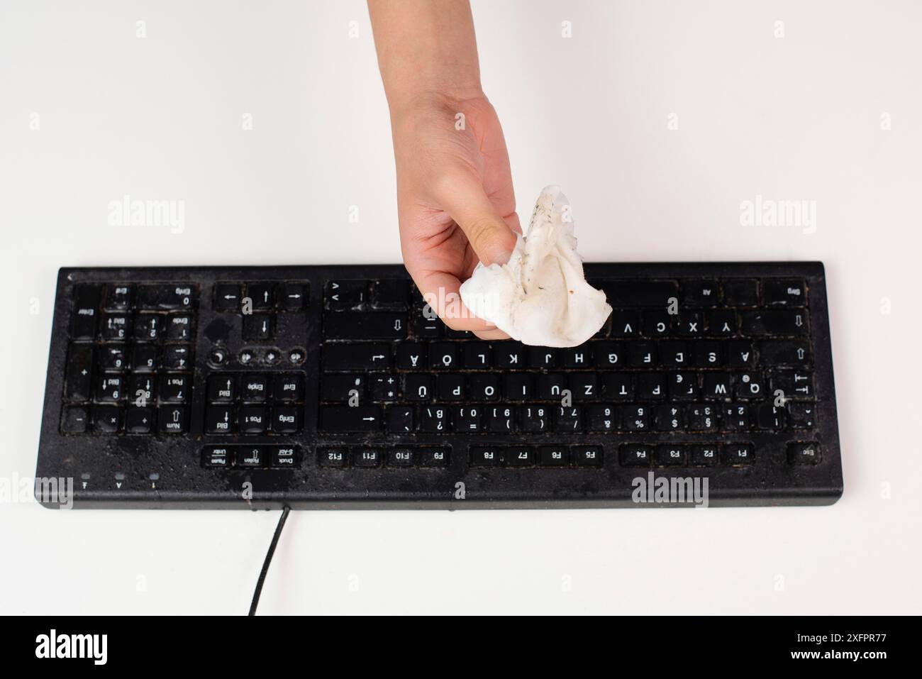 Cleaning computer keyboard in office with a wet wipe rag, dusty and ...