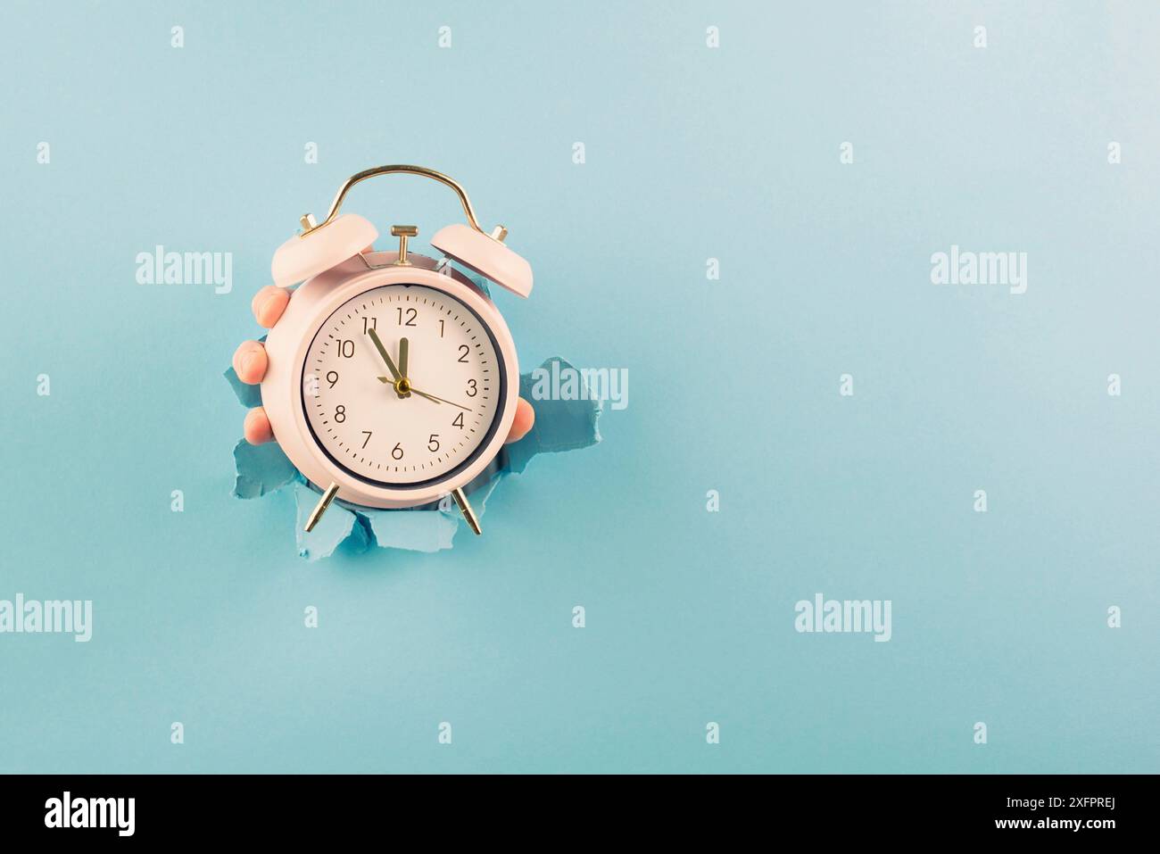 Hand holding alarm clock, torn paper hole, time management, reminder ...
