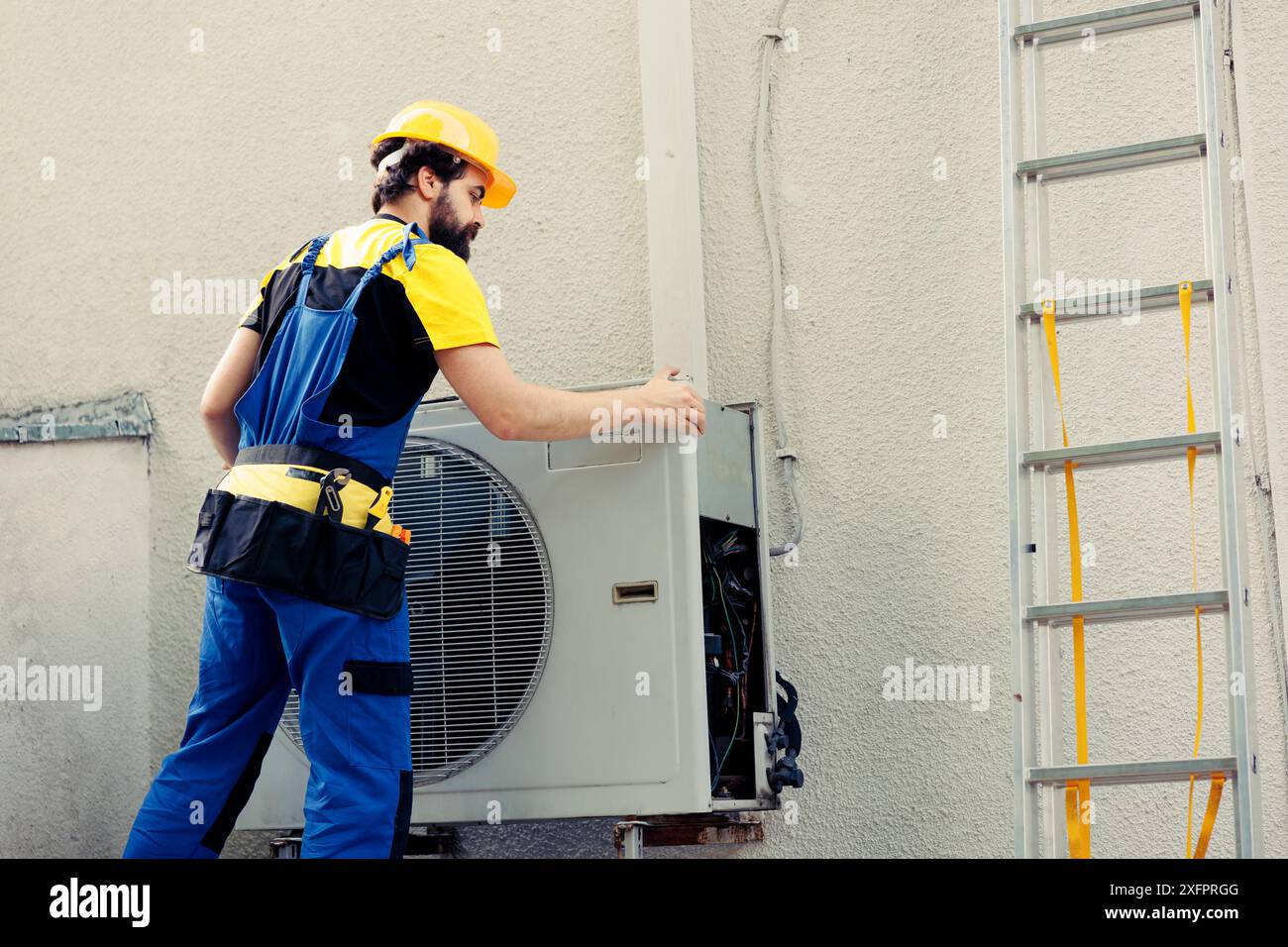 Skilled wireman starting work on malfunctioning air conditioner, using ...