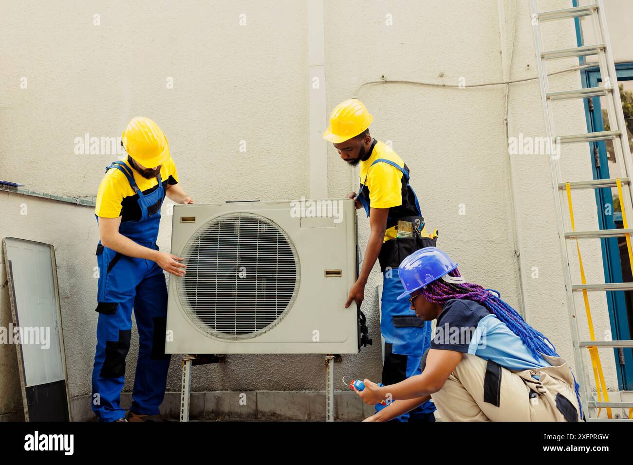 Proficient workers putting new external air conditioner in place for ...