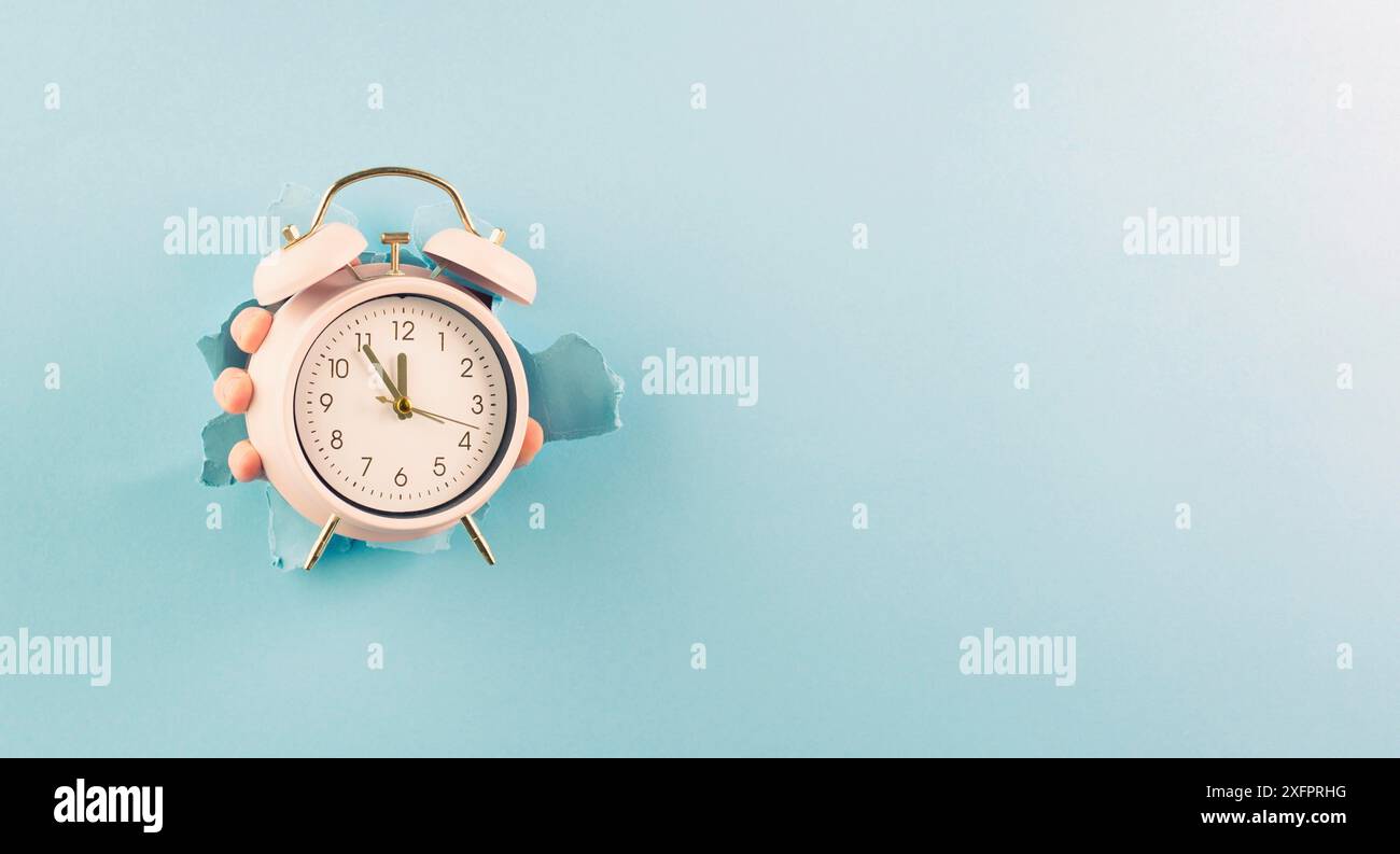 Hand holding alarm clock, torn paper hole, time management, reminder ...