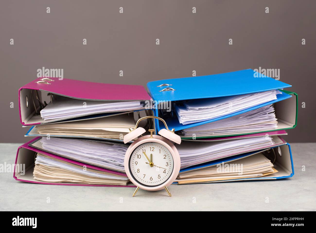 Alarm clock standing next to pile of file folders, burnout, stress and ...