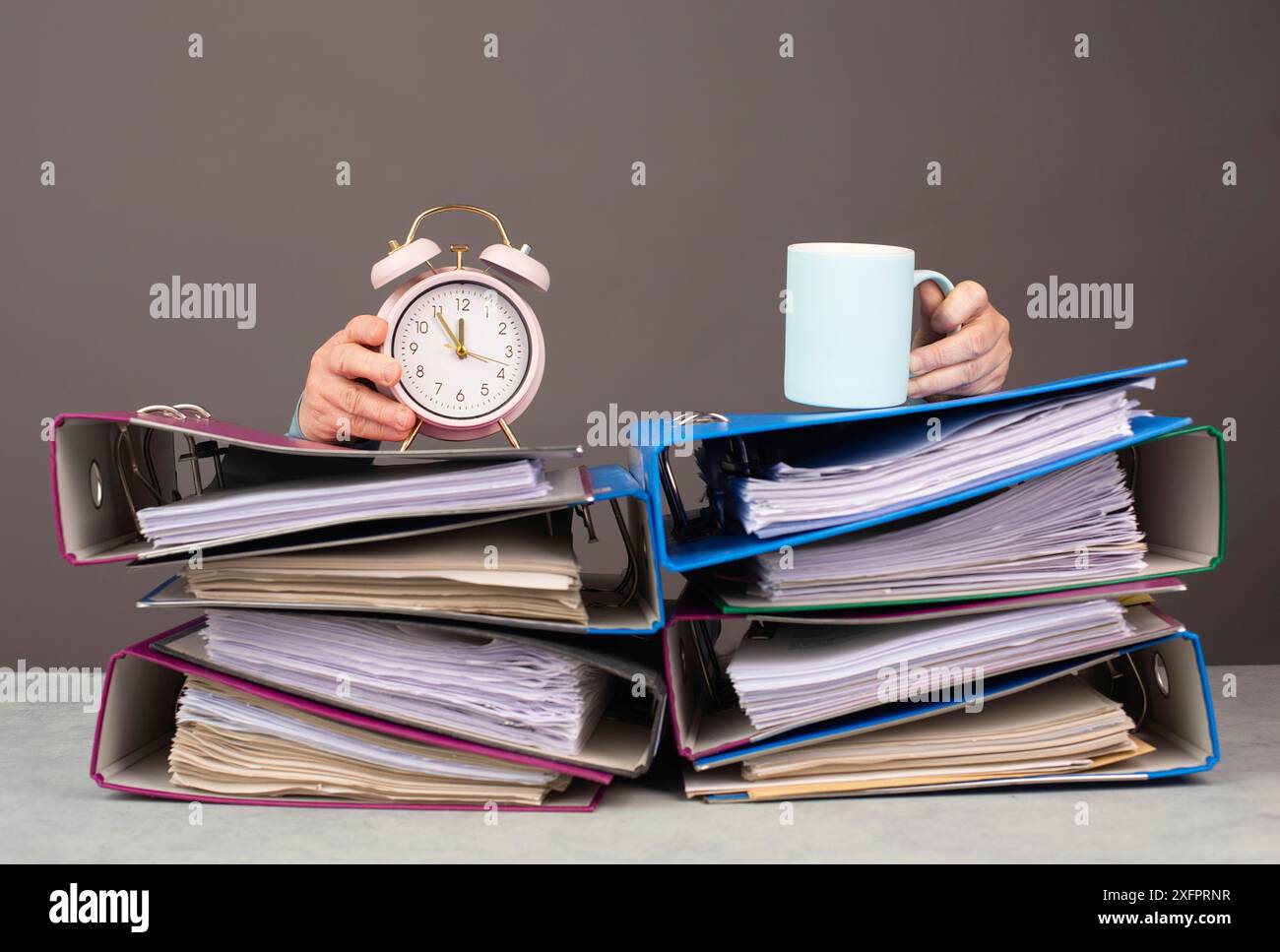 Exhausted tired woman with coffee and alarm clock, pile of file folders ...