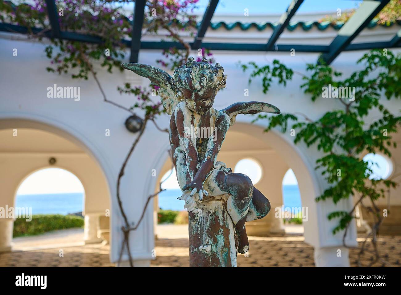 Bronze angel statue in front of arched windows overlooking the sea ...