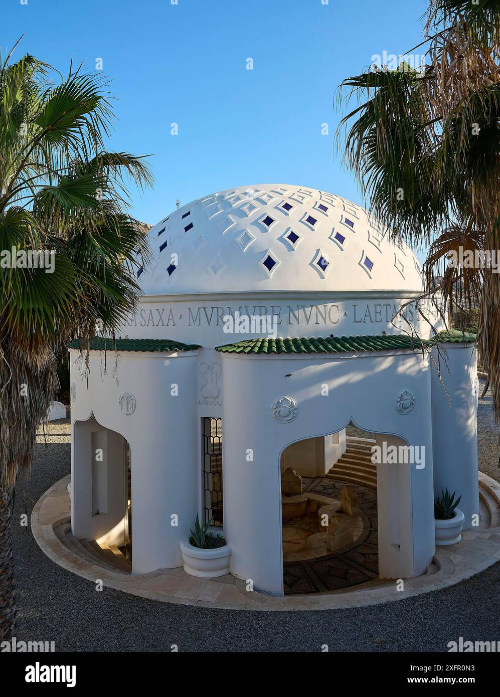 White, decorative domed architecture surrounded by palm trees under a ...