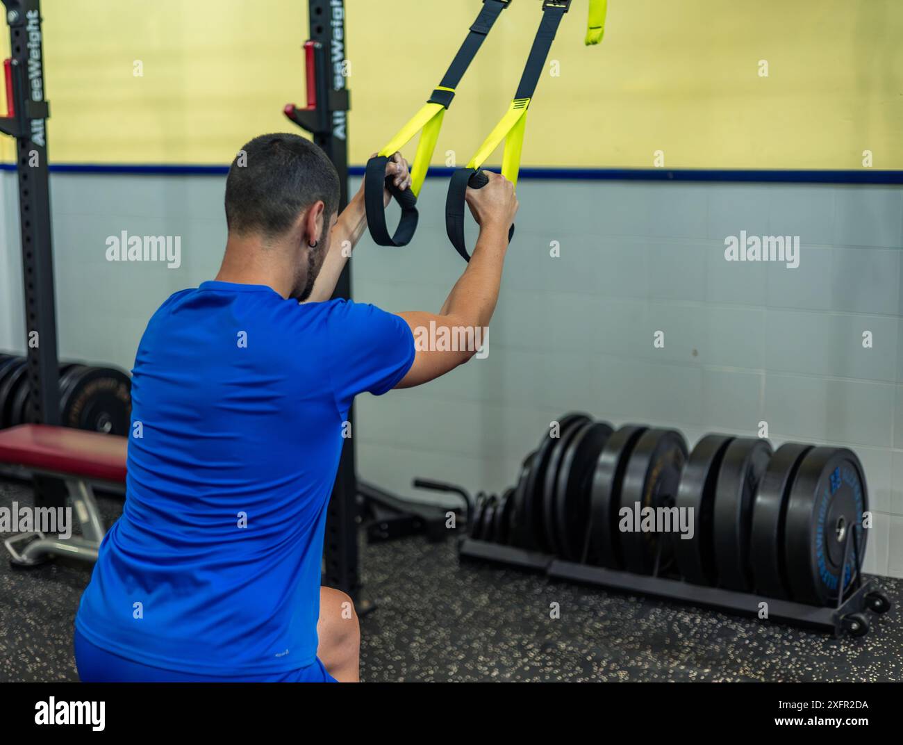 An athletic man performs a leg workout using TRX suspension training ...