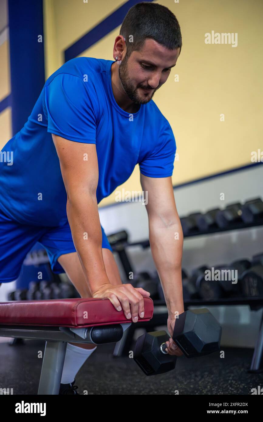 vertical young athlete performs back exercises using a dumbbell while ...