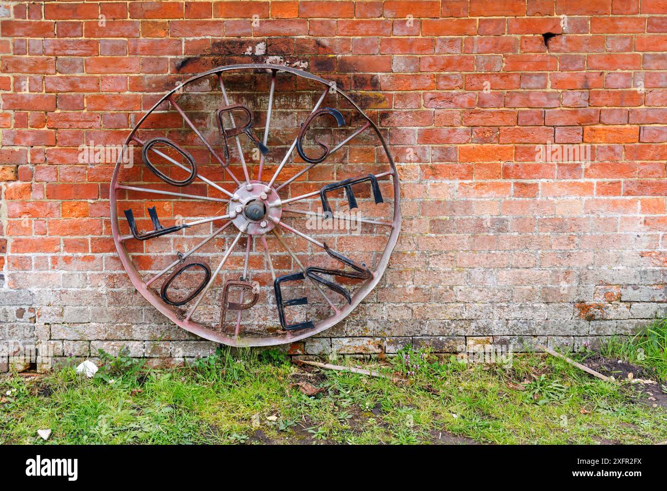 Iron wheel with 'Forge Open' on a former blacksmith's building wall in ...