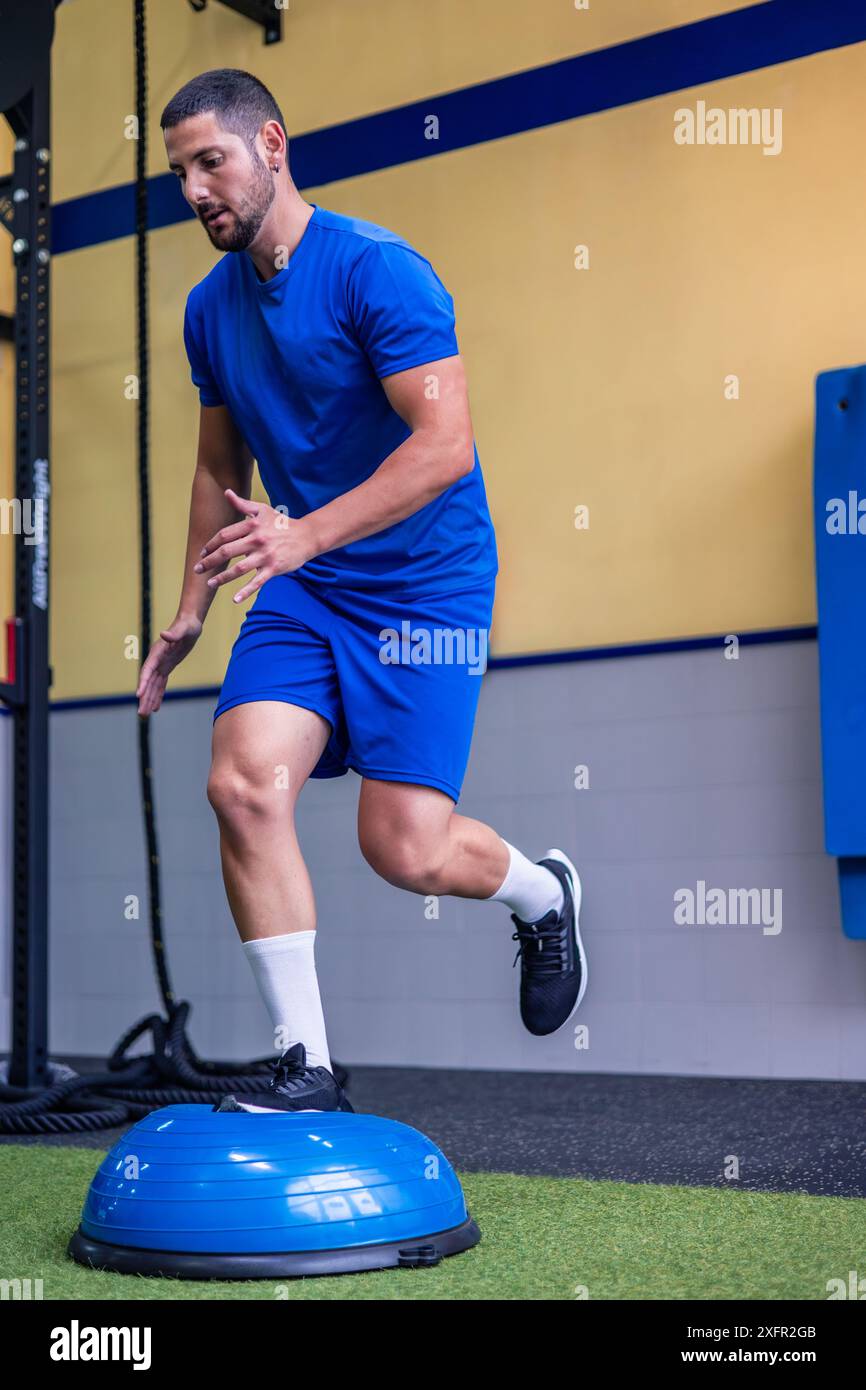 vertical young athlete is engaged in a leg and balance workout using a ...
