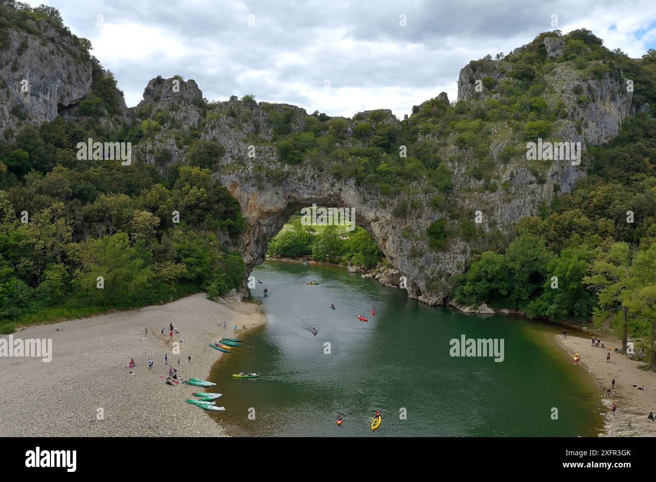 People canoeing under the Pont d'Arc, natural rock arch over river ...