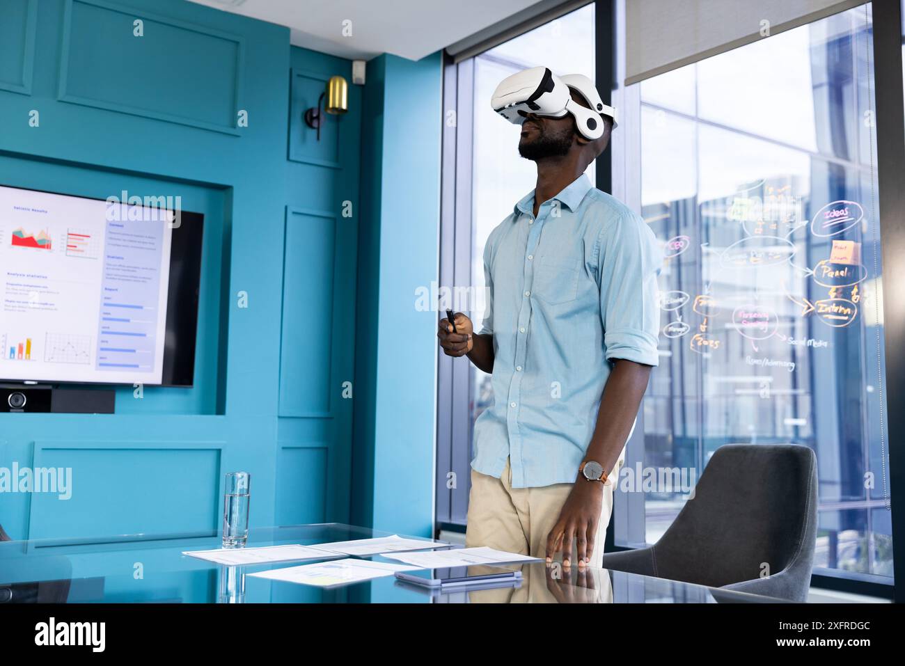 Using VR headset, man standing in modern office with documents on table ...