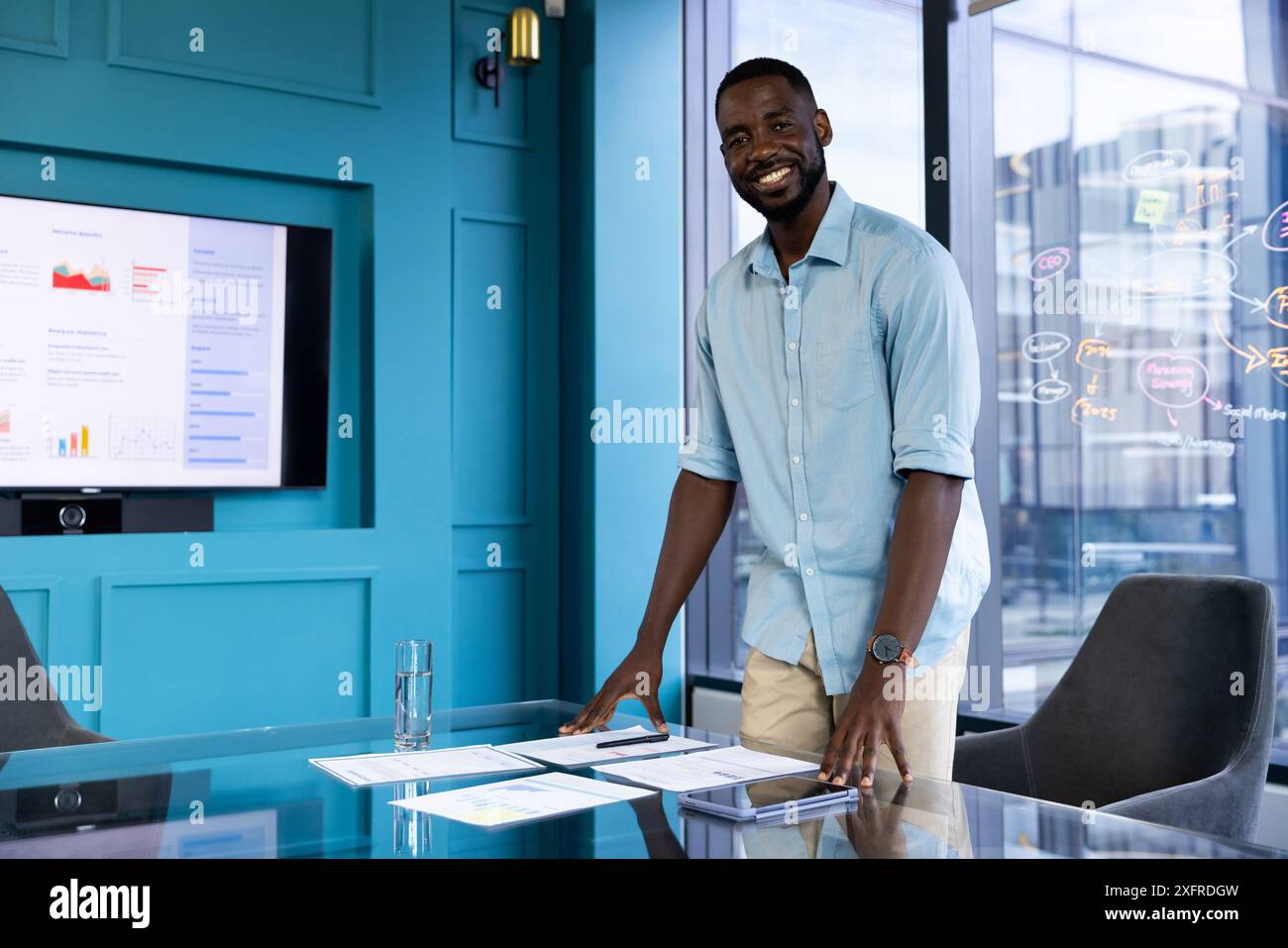 Standing at conference table with documents, smiling businessman ...