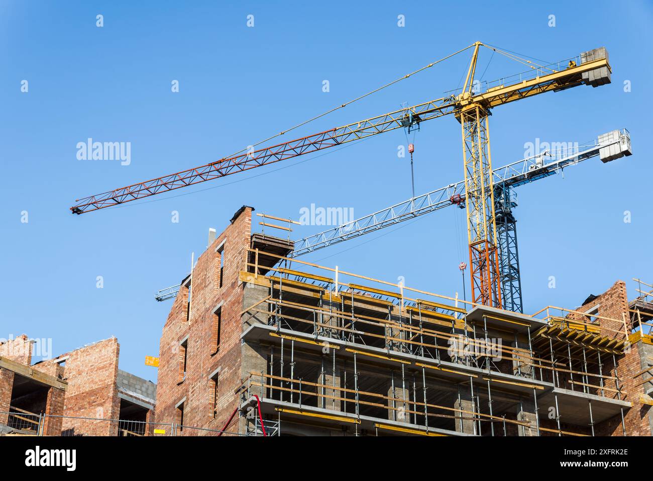 A Pair Of Construction Cranes In Building Site On Blue Sky Background ...