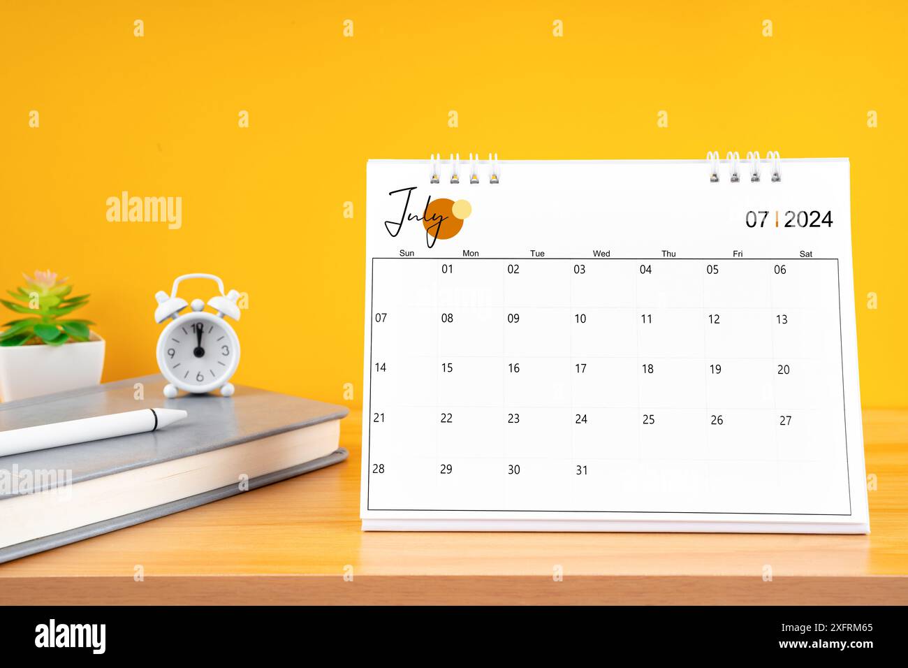 July desk calendar for 2024 year on work table with yellow color ...