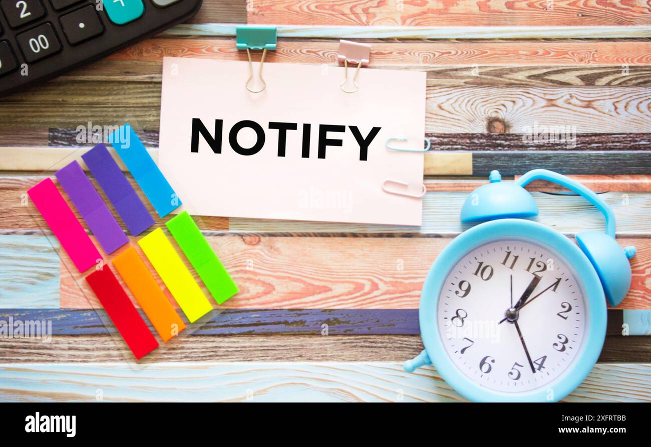 notify word written on a sticky note next to office supplies Stock ...