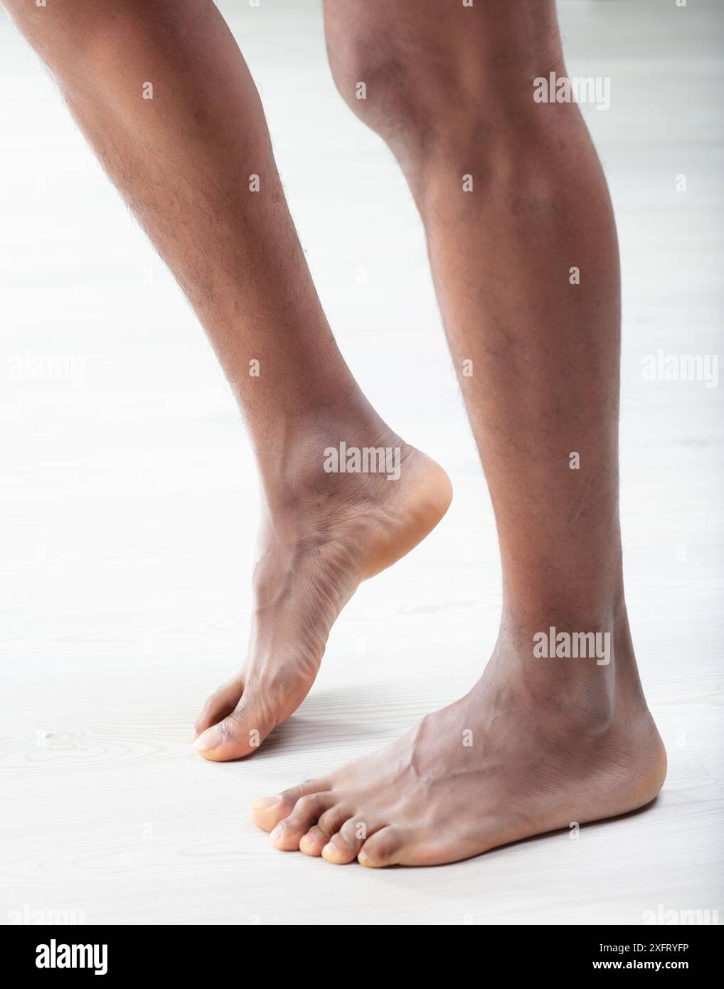 man stands on his toes, indicating possible foot or leg pain. The close ...