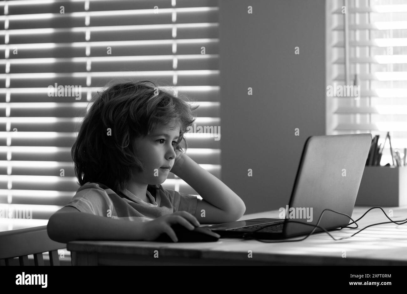 Smart little caucasian boy child sit at table study at laptop notebook ...