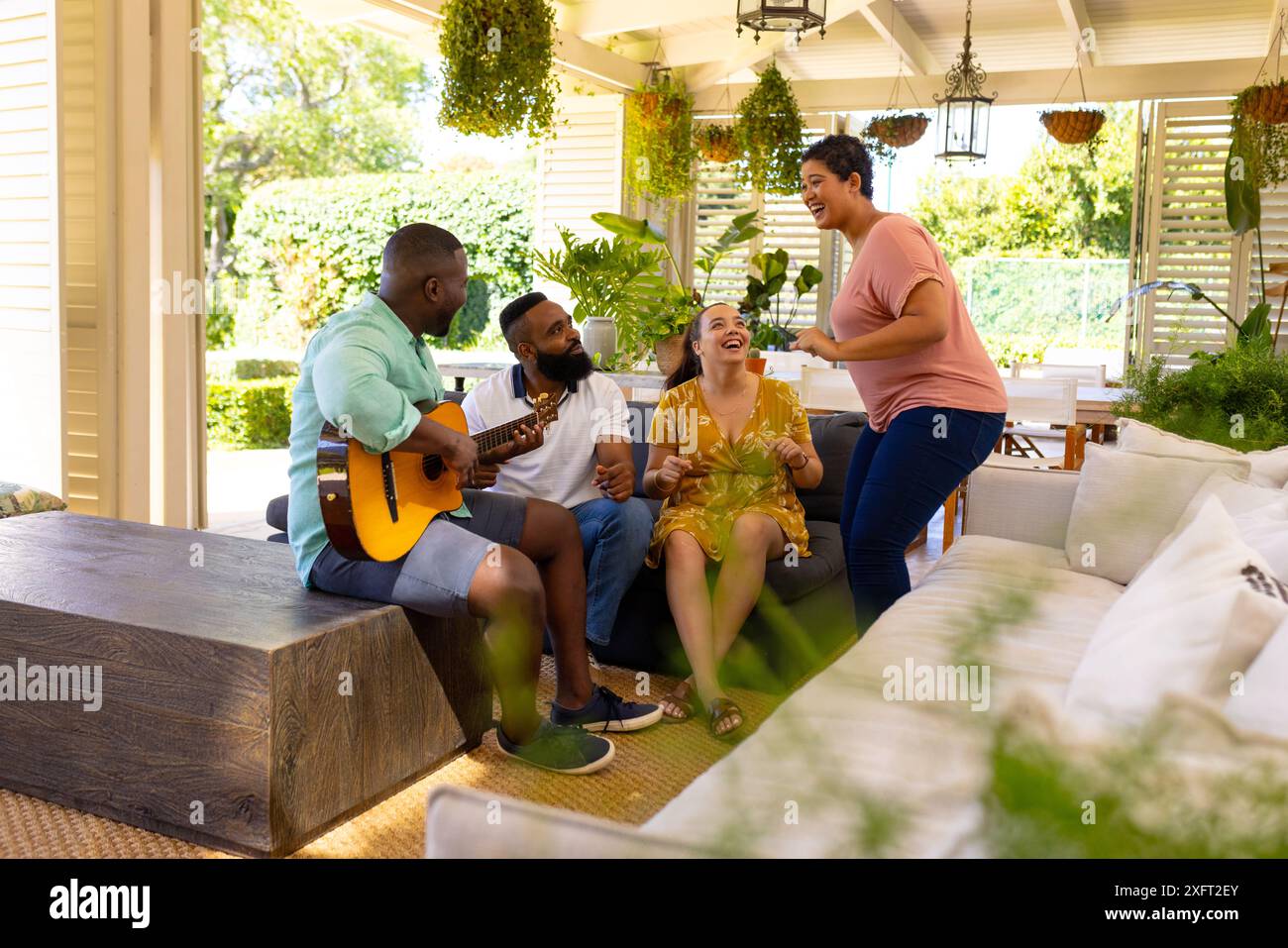 Playing guitar and singing, diverse friends enjoying time together on ...