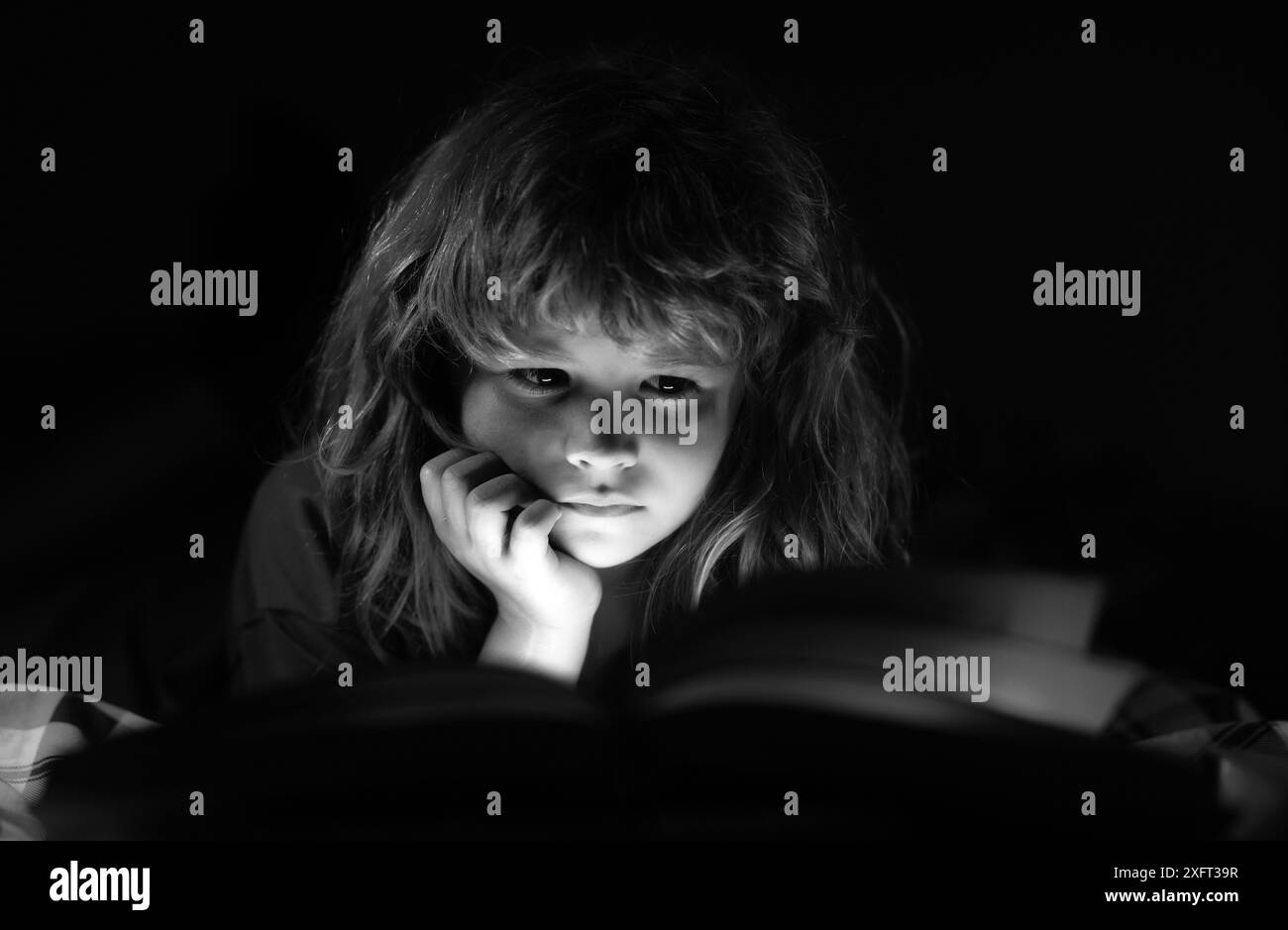 Child little boy reading a book in the dark home. Kids face with night ...