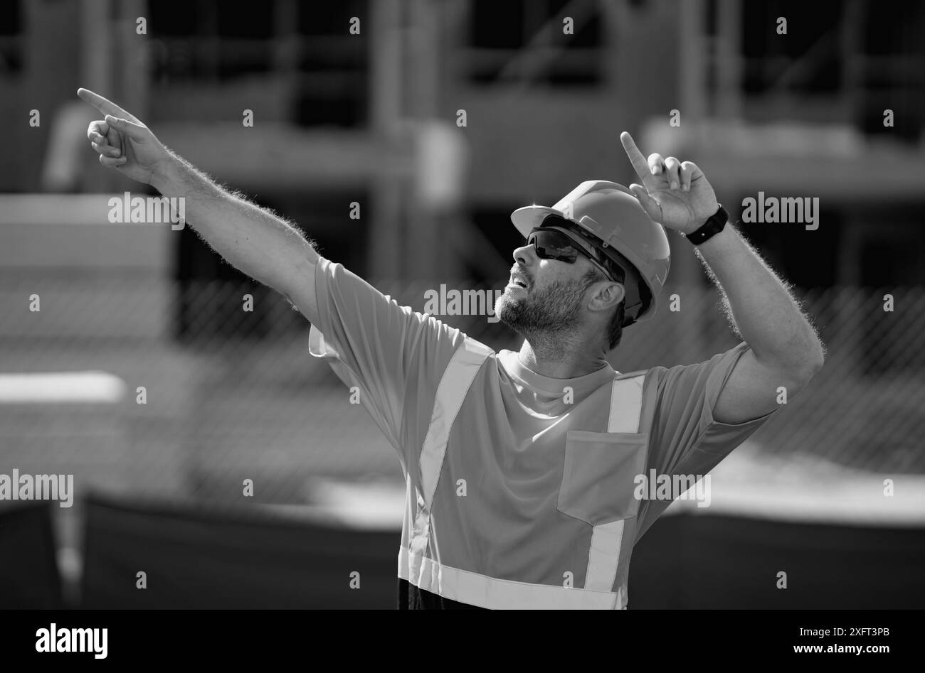 Construction site worker in helmet working outdoor. Worker pointing out ...