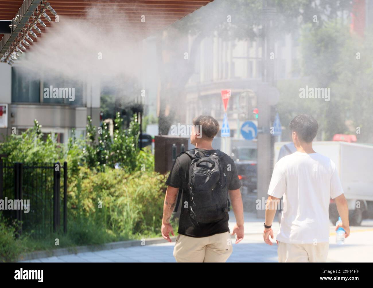 Tokyo, Japan. 5th July, 2024. People walk under water mist to cool down ...