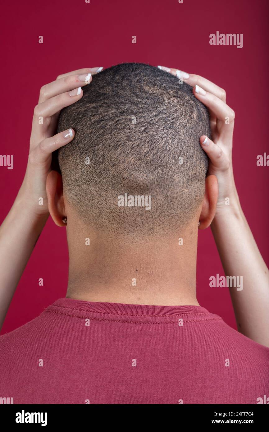 black man's shaved head is gently held by a white woman's hands. This ...