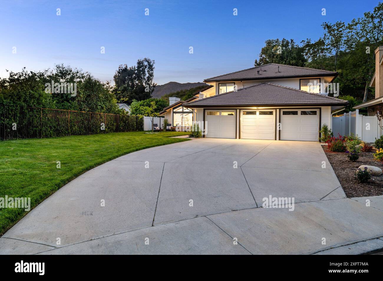 A modern two-story house with a three-car garage, large driveway, and ...