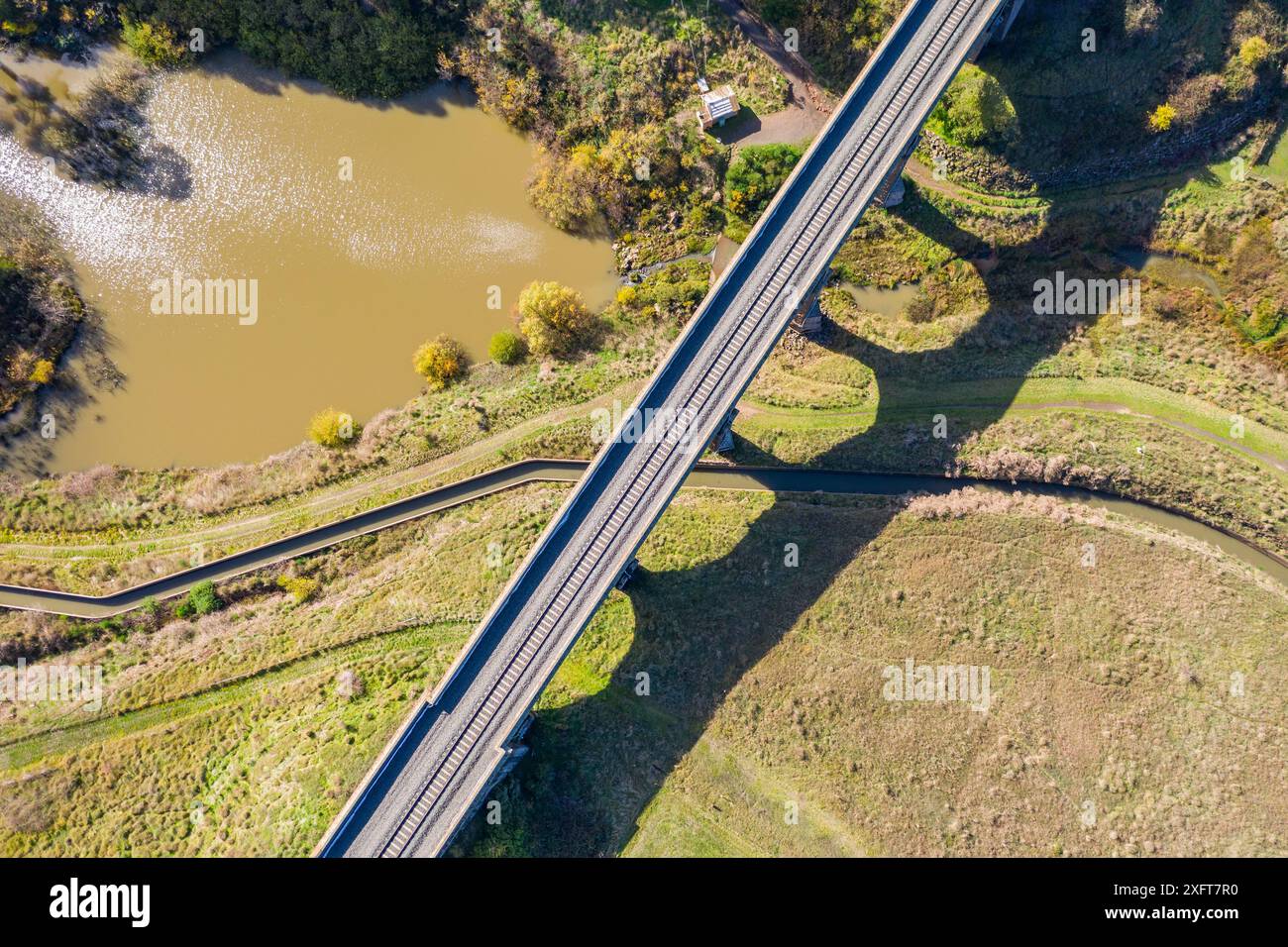 Aerial view of a railway viaduct with stone arches casting shadows over ...