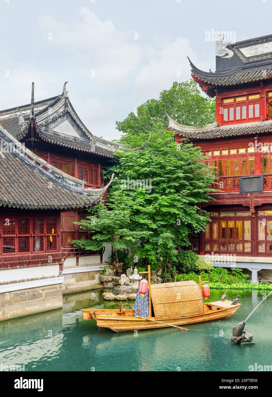 Scenic view of traditional Chinese wooden boat and pond among buildings ...