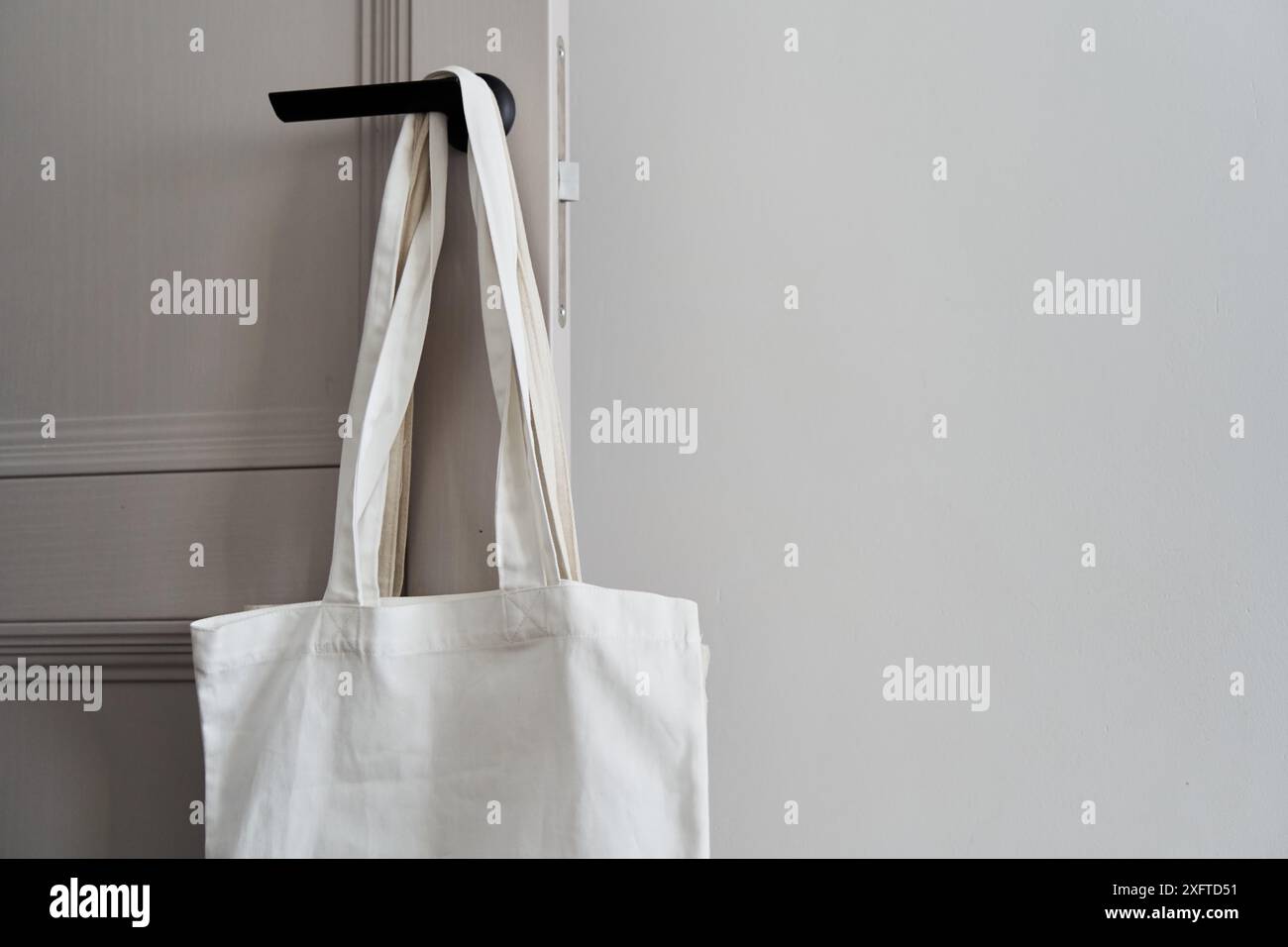 White eco friendly bag hanging on the door handle. Canvas tote bag ...