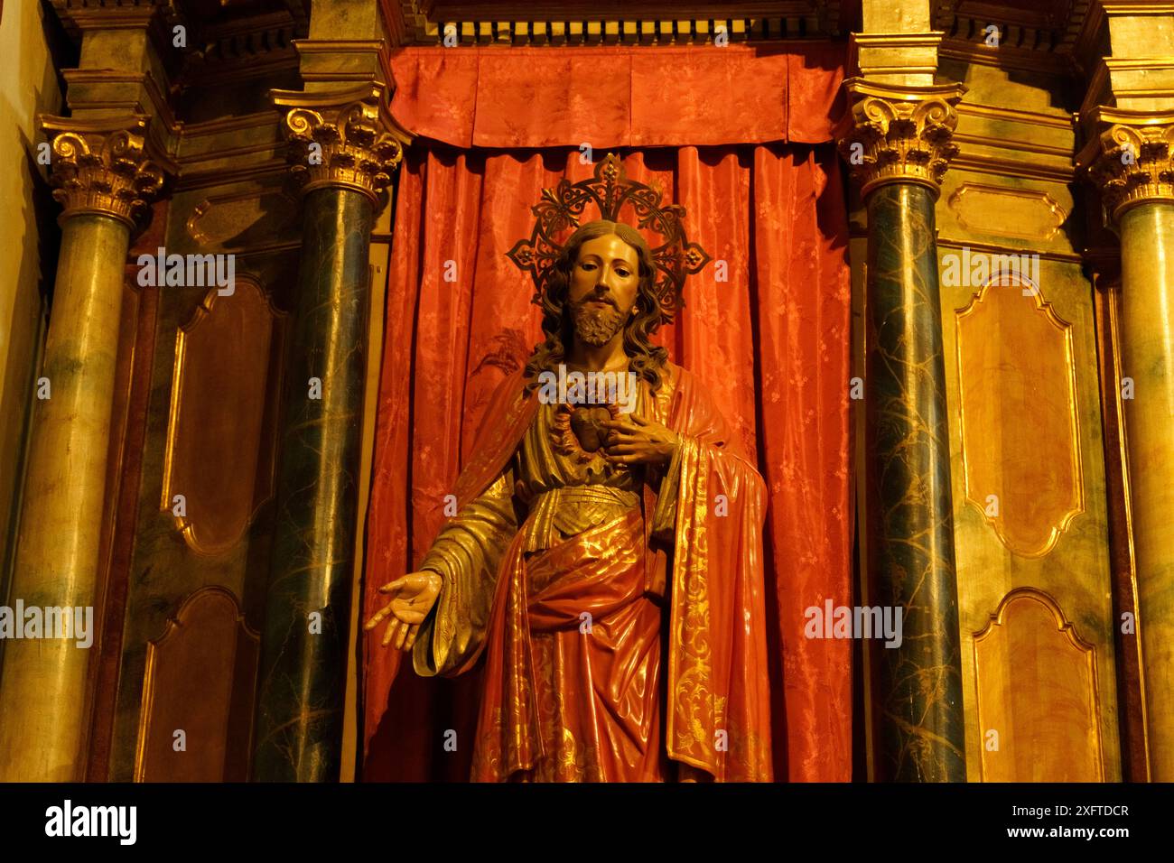 A statue of Jesus stands prominently in a church, surrounded by pews ...