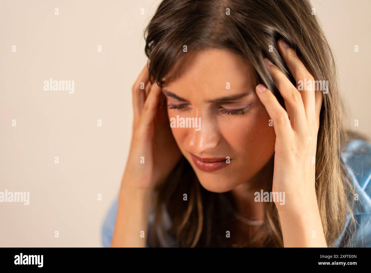 Young woman experiencing stress and headache, holding her head in pain ...