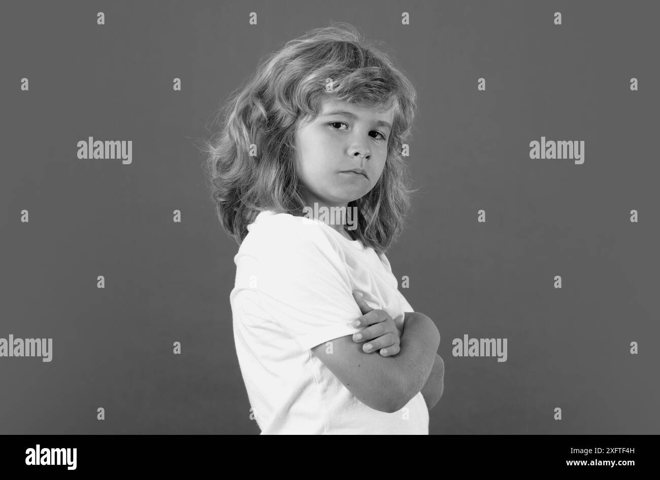 Portrait of child with crossed arms on blue isolated studio background ...