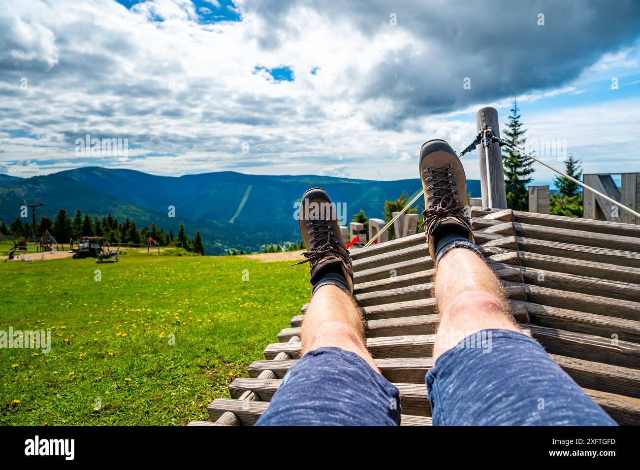 Mountain hiker is resting at wooden desk on top of hill. View of hiker ...