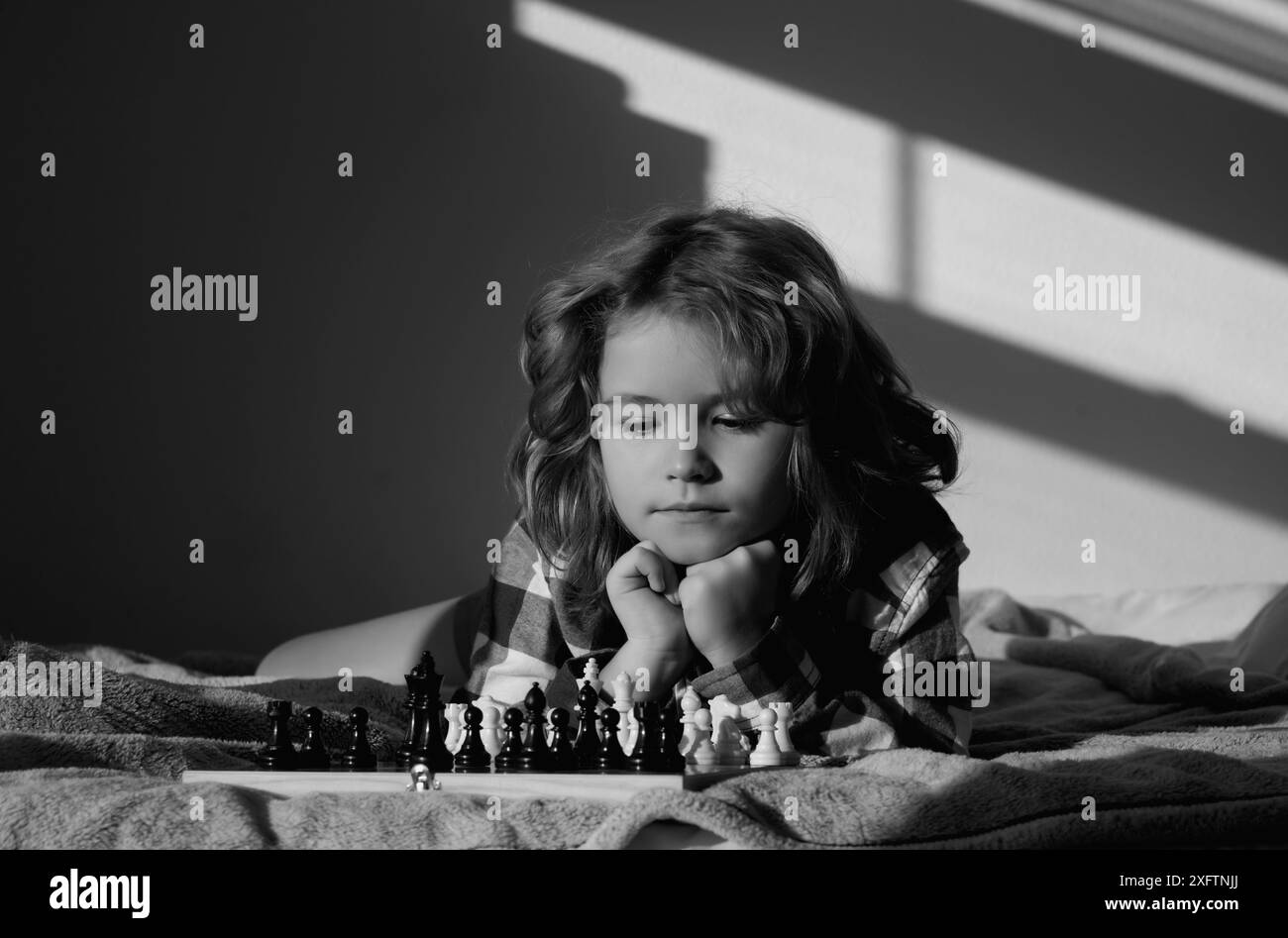 Cute boy are playing chess at home. Clever concentrated and thinking ...