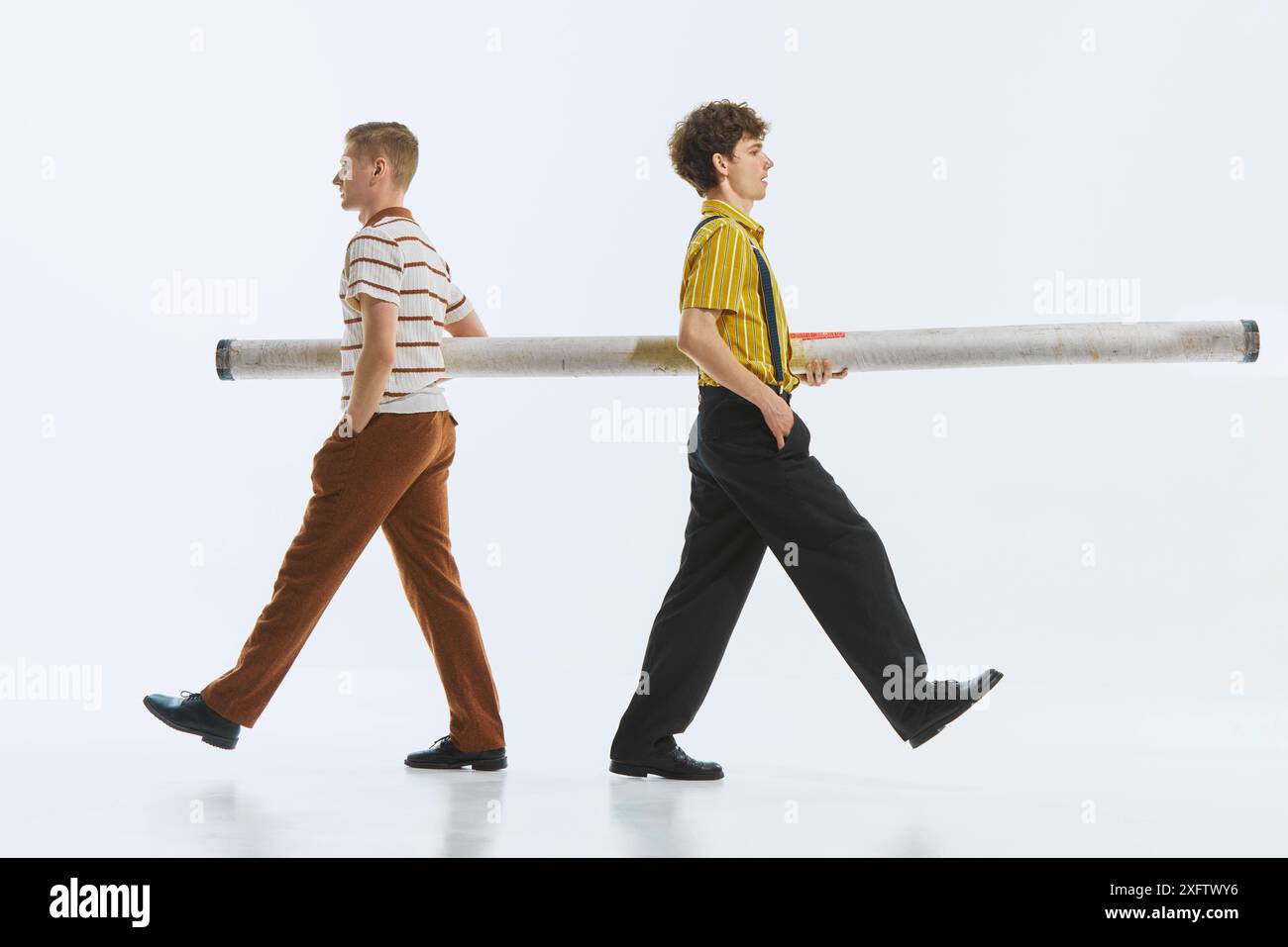 Two men in retro attire carry long tube isolated on white background ...