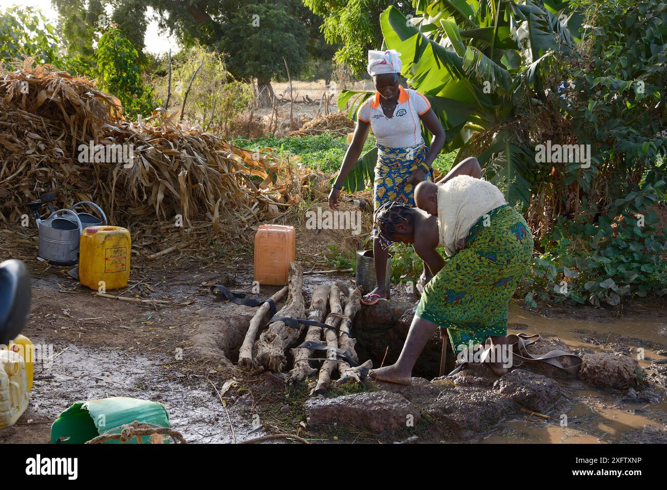 Woman with baby on back pulling up water from the well, Burkina Faso ...