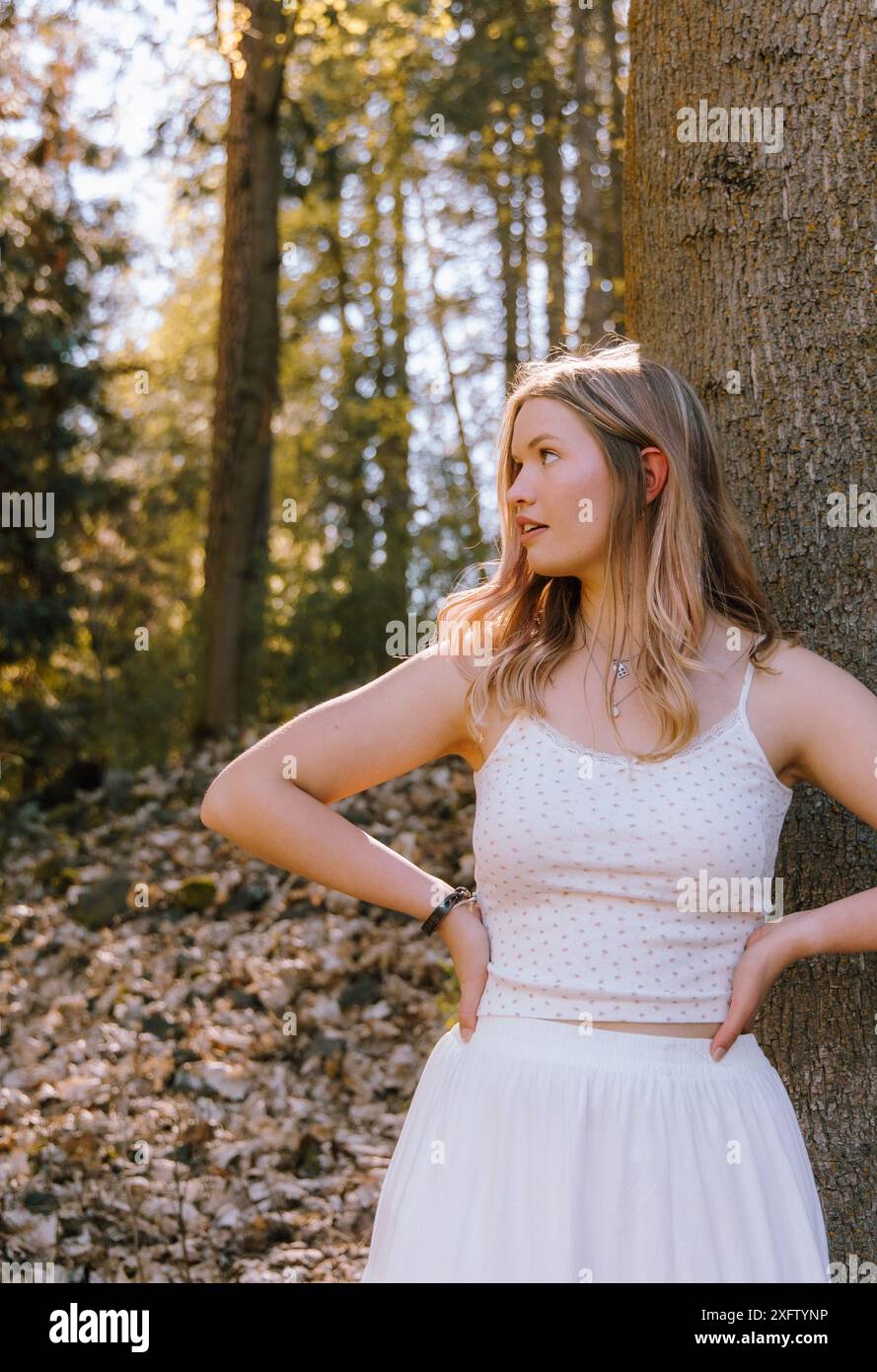 Woman standing by a tree in the forest, wearing a white outfit Stock ...