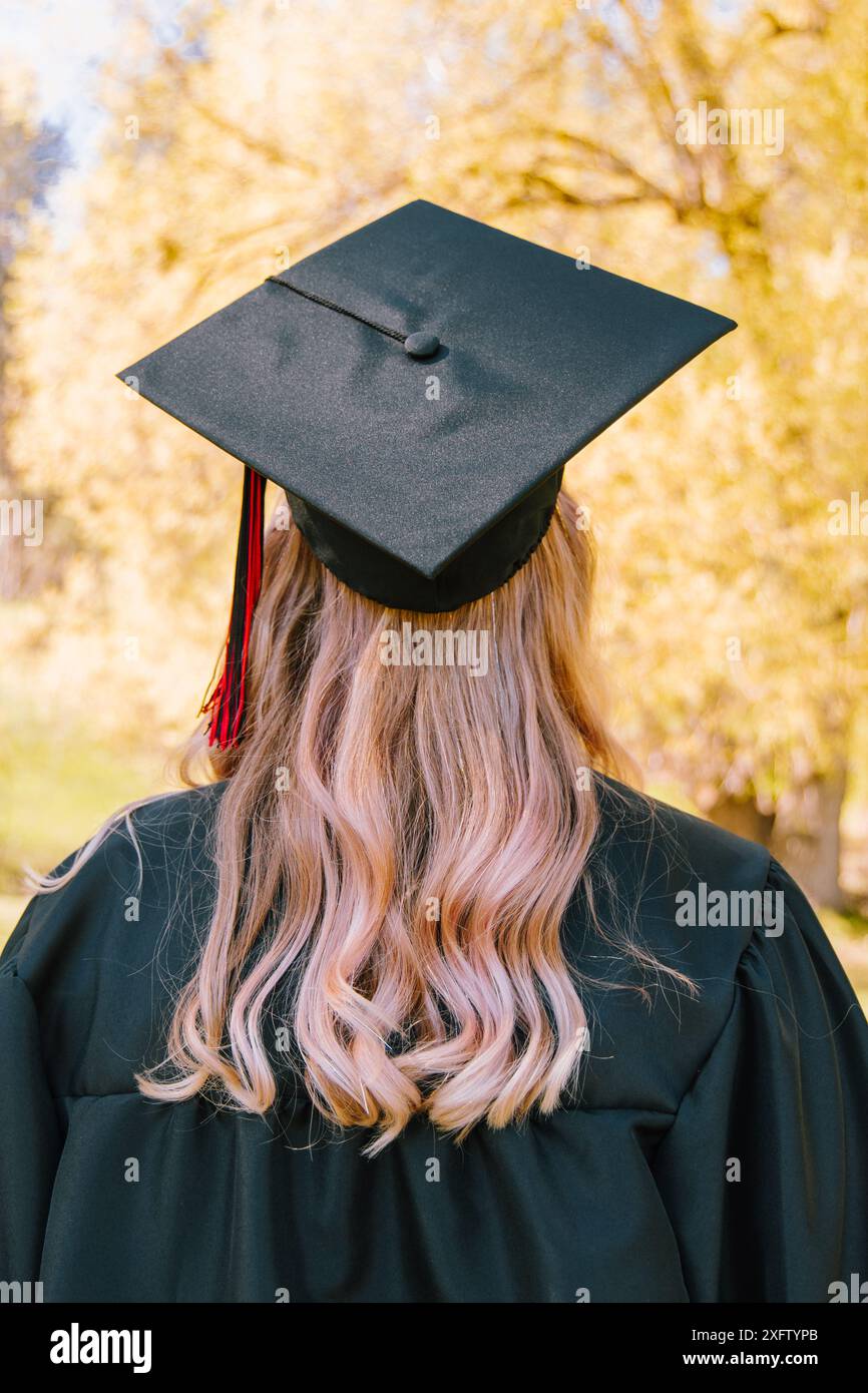 Graduate from behind wearing cap and gown, standing outdoors Stock ...