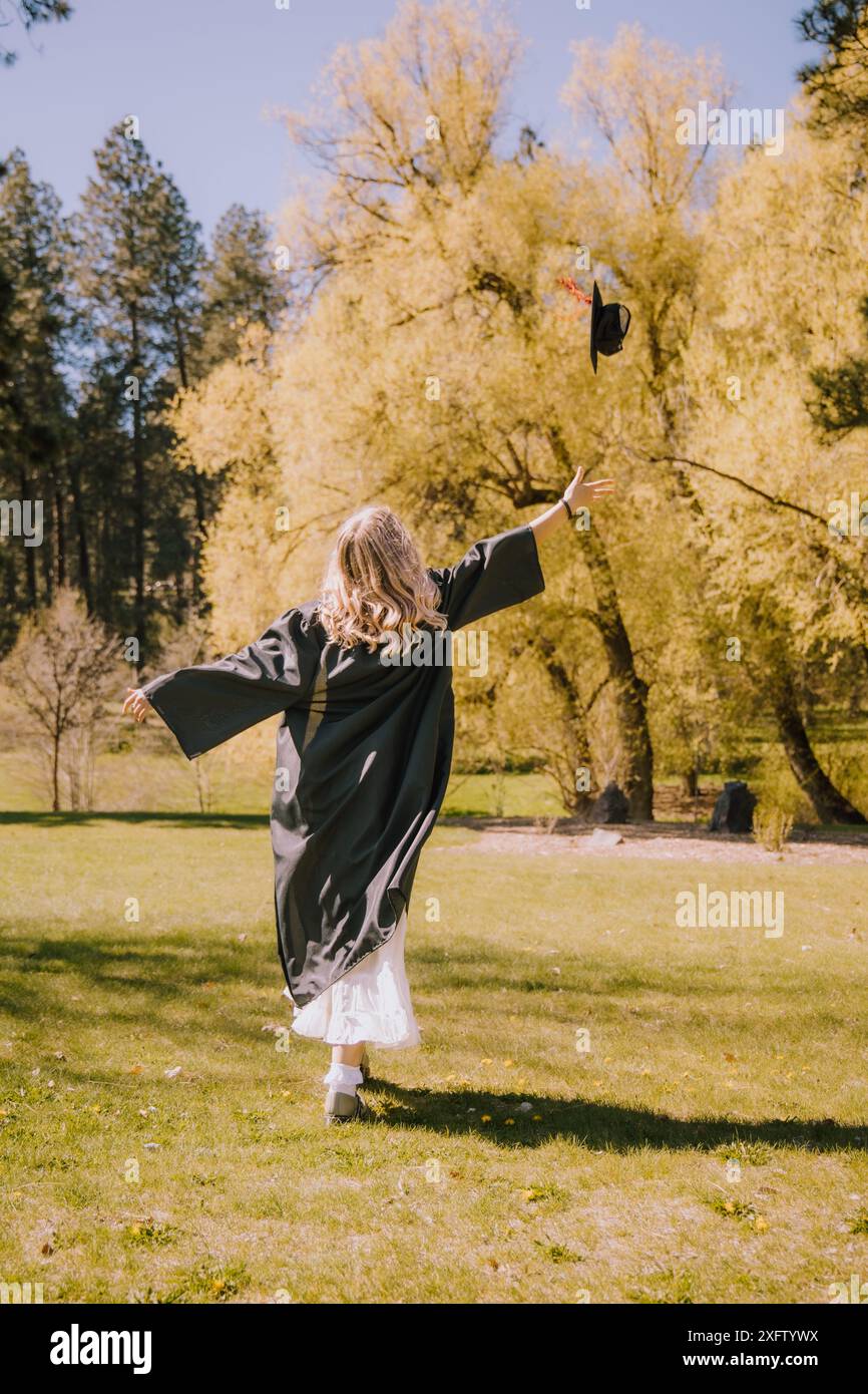 Graduate throwing cap in the air, celebrating in a sunny park Stock ...