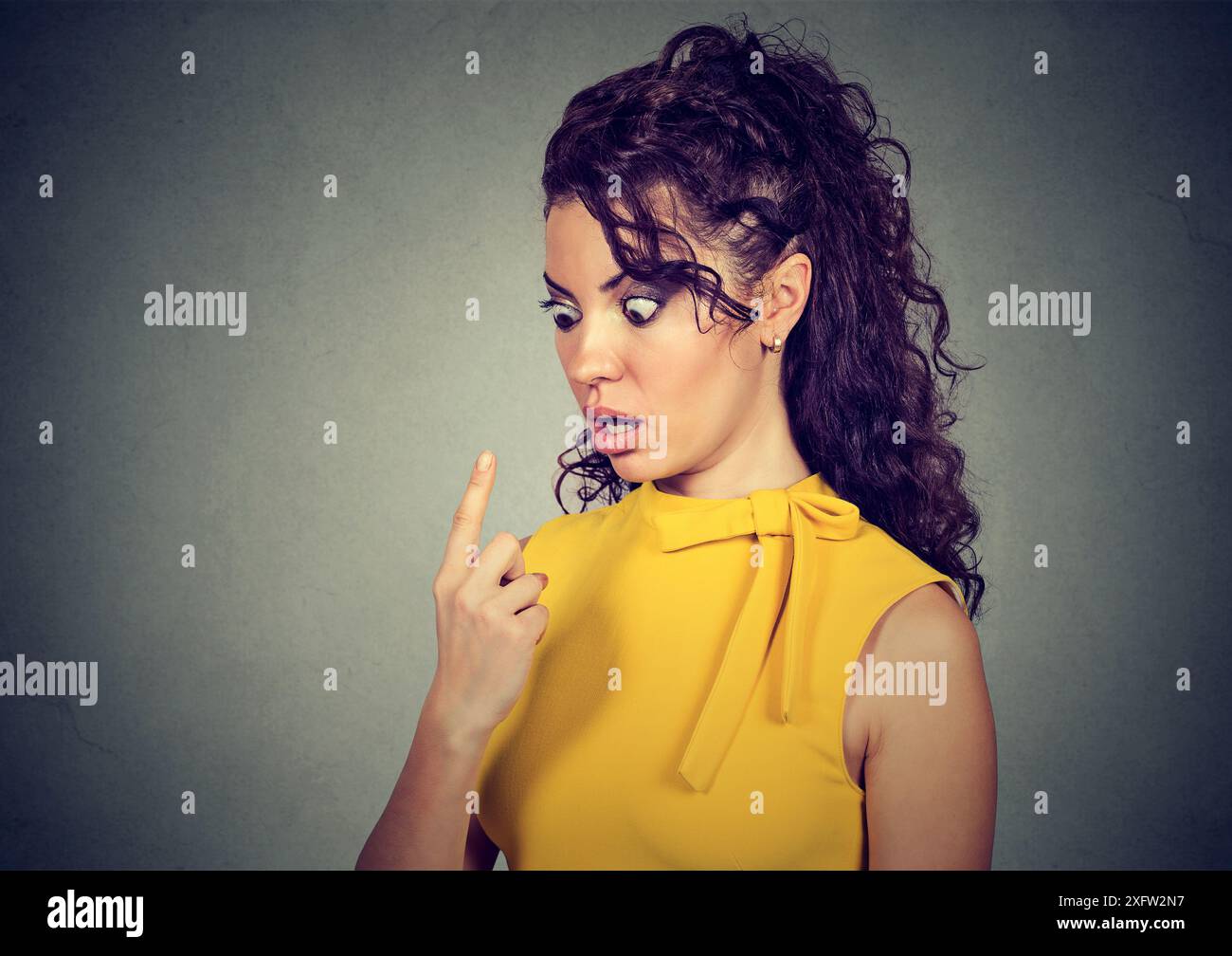 Shocked young woman looking at her index finger Stock Photo - Alamy