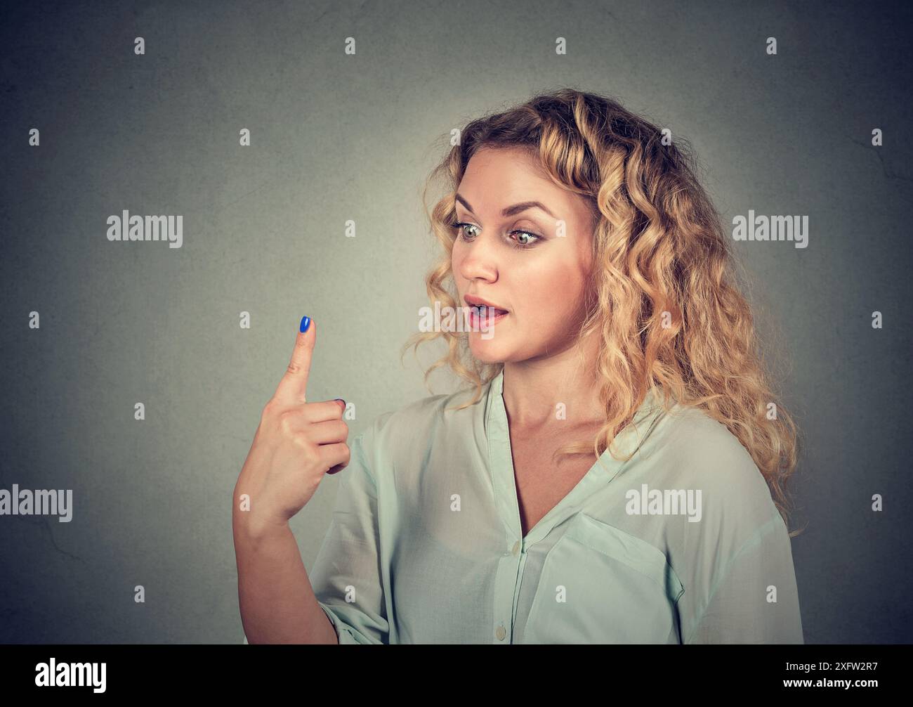 Shocked young woman looking at her index finger Stock Photo - Alamy