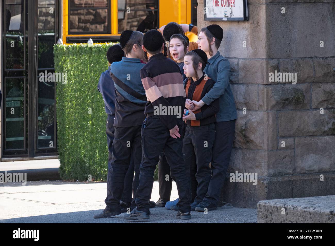 A group of orthodox Jewish yeshiva students huddle together on a street ...