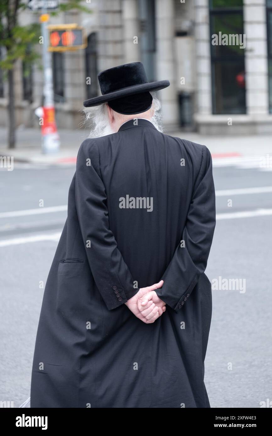 An anonymous senior orthodox Jewish man walking with his hands together ...